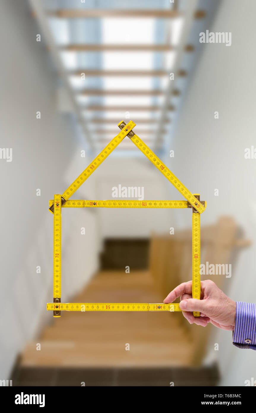 shell of house under construction with folding ruler in hand of real ...