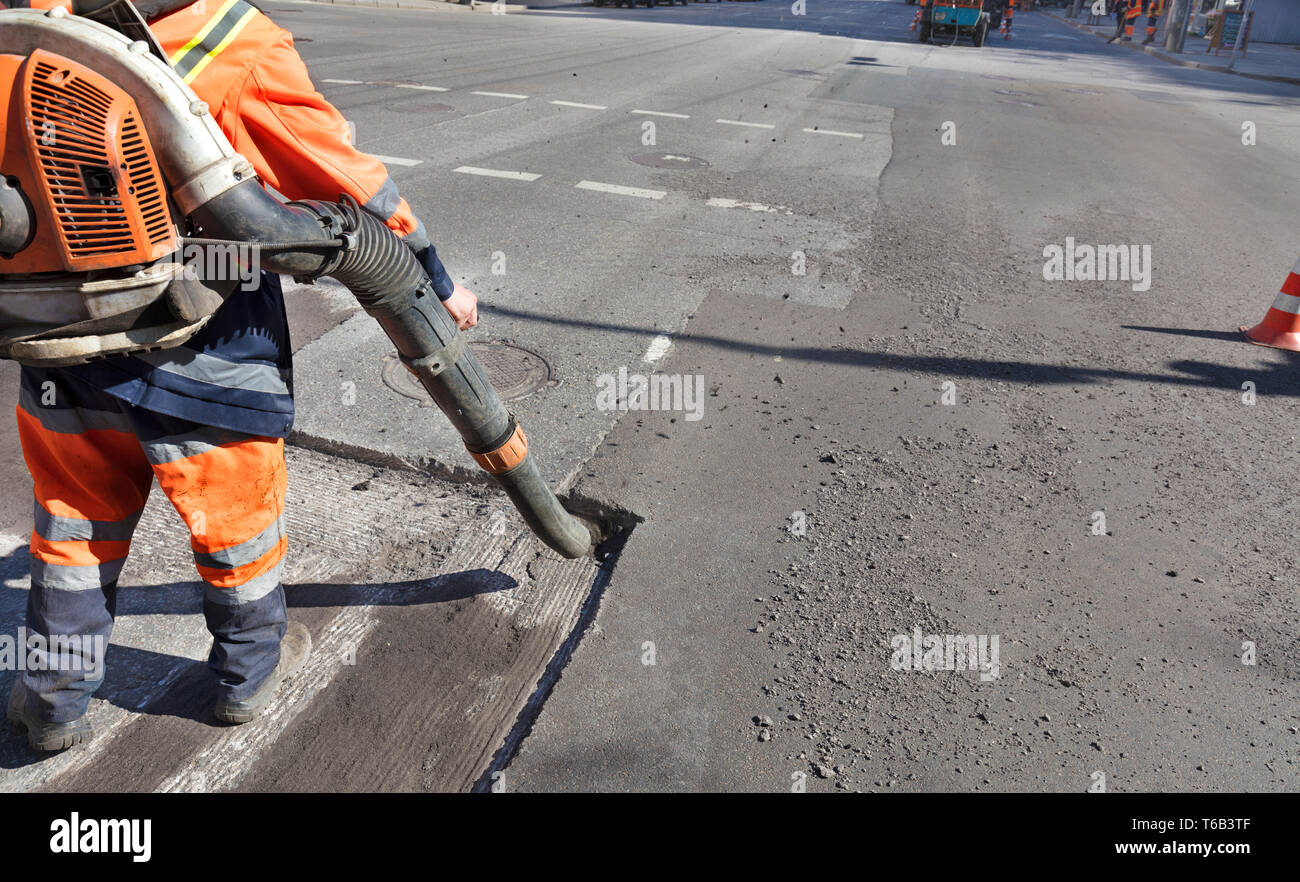 Worker with blower posing, cleaning out the dust with a leaf-blower for ...