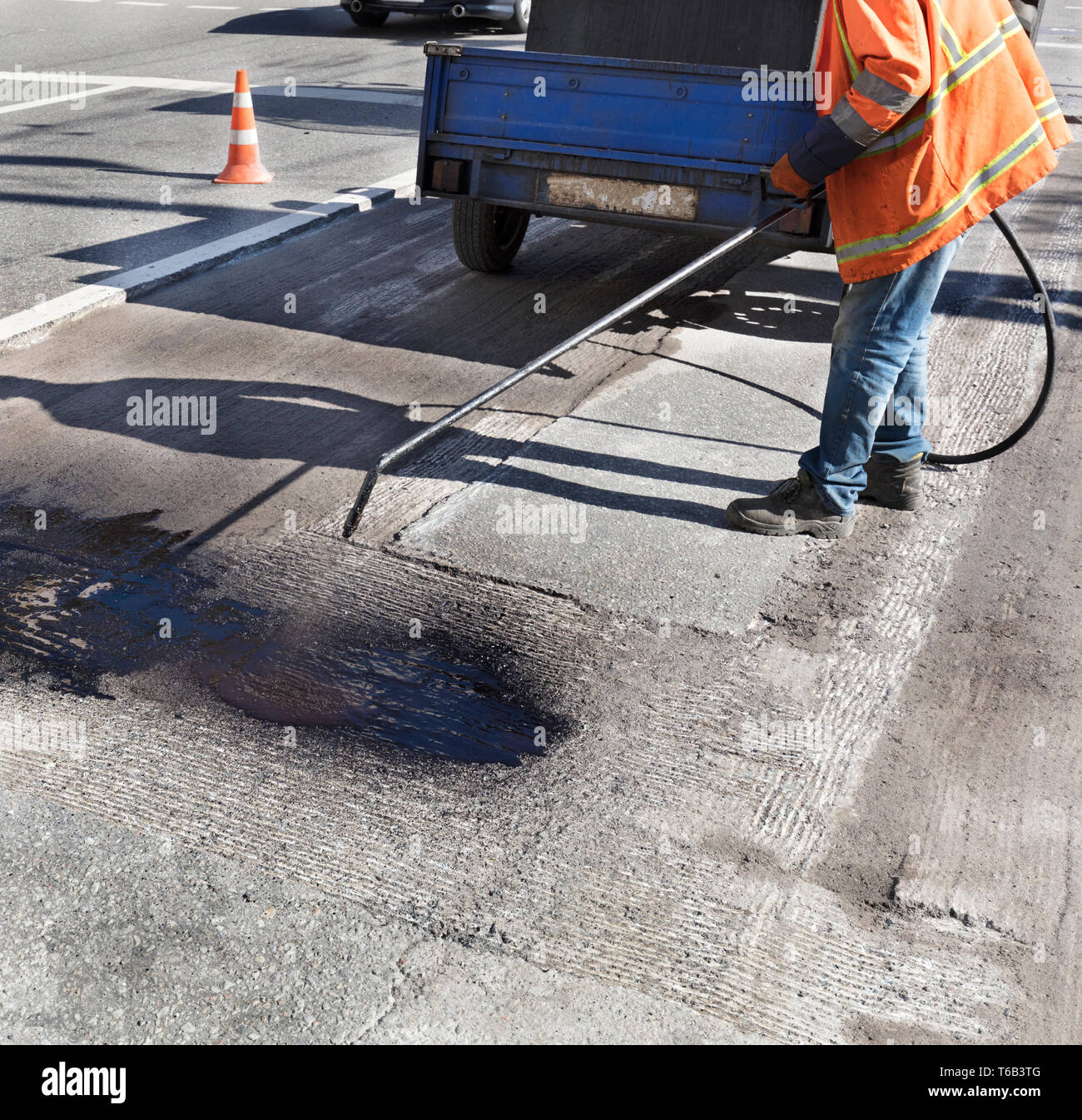 The road maintenance worker sprays the bitumen mixture onto the cleaned ...