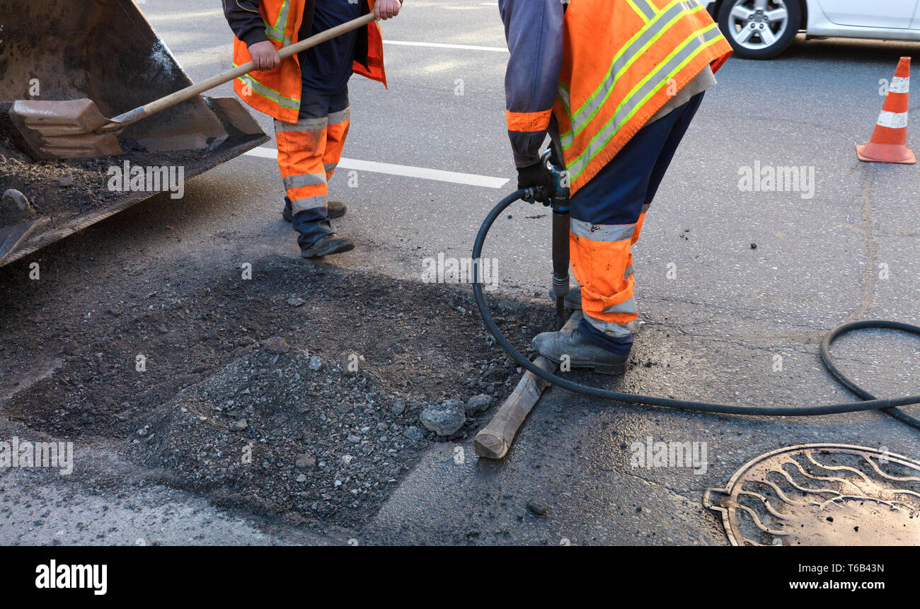 a brigade of servants for road maintenance removes the old asphalt with ...