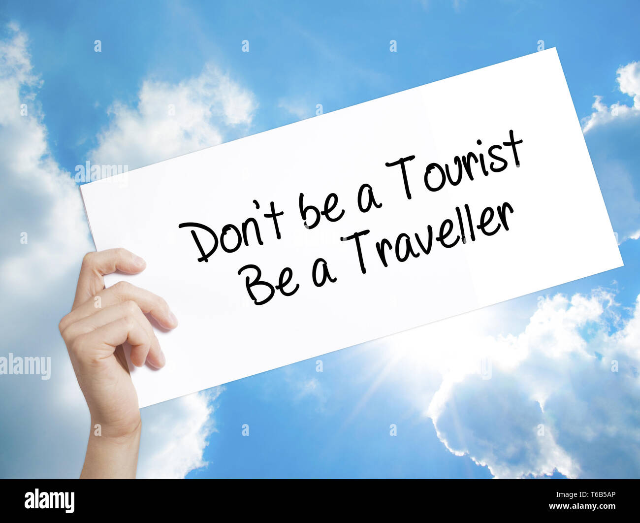 Don't be a Tourist Be a Traveller Sign on white paper. Man Hand Holding ...