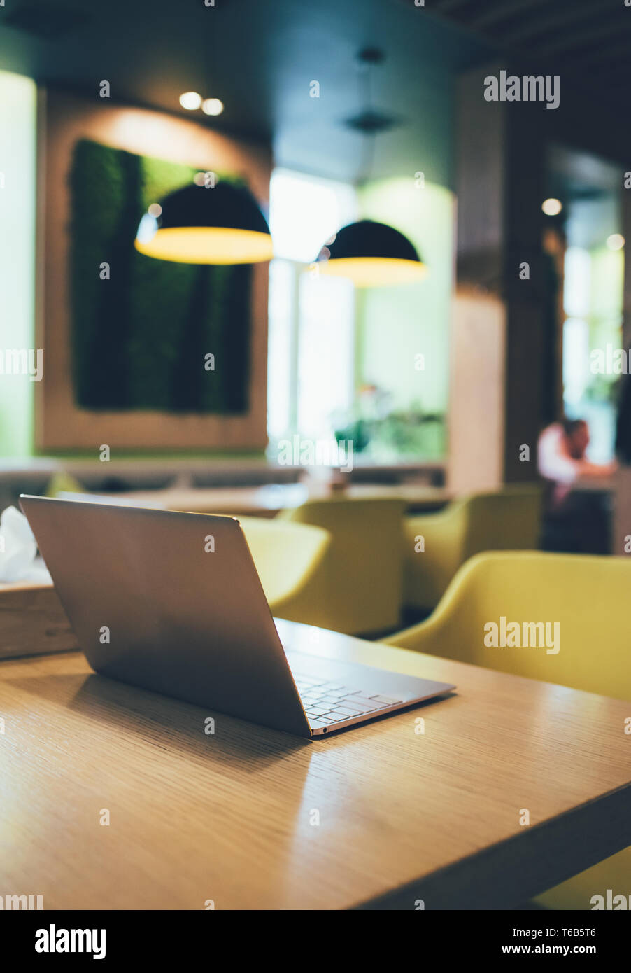 Open laptop on the table in city cafe interior, cozy business coworking ...