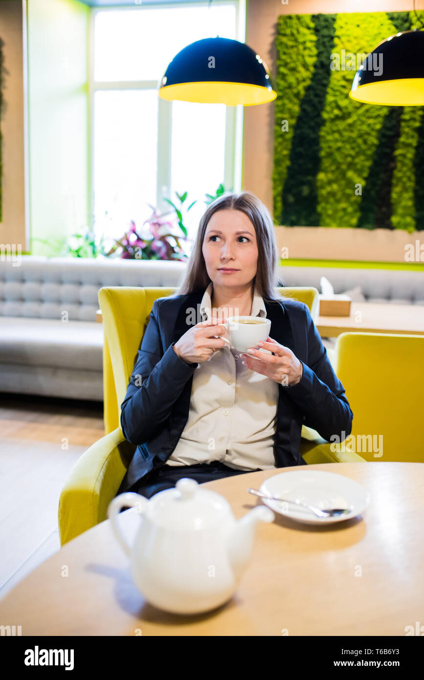 Young business lady drinking herbal tea in city cafe, woman in suit in ...