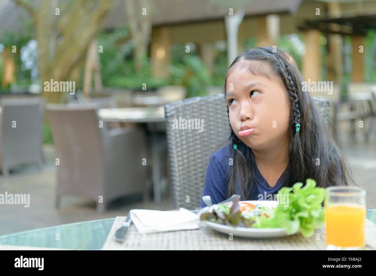 asian child girl with expression of disgust against vegetables in salad ...