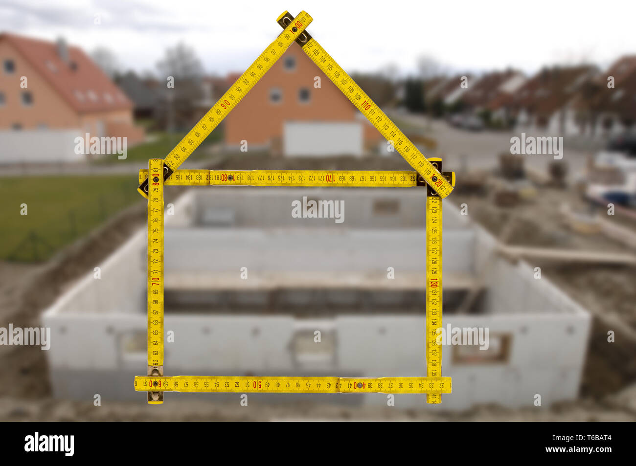 shell of house under construction with folding ruler in hand of real ...