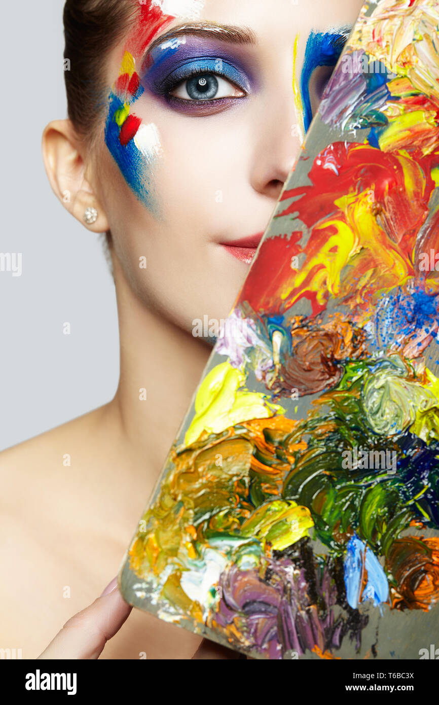 Young female painter with color palette and acrylic paint on face Stock ...