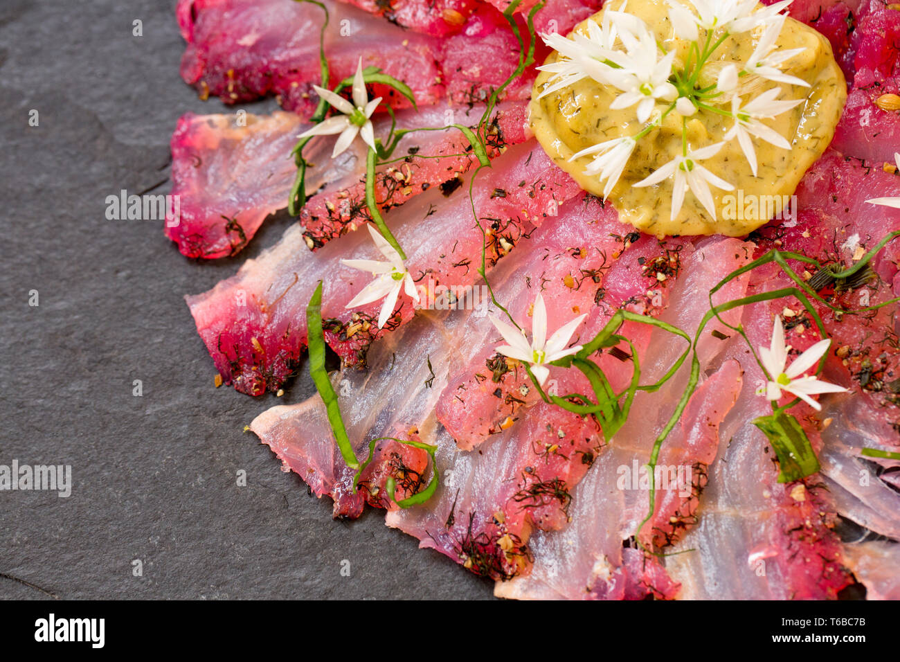 Slices of pollack gravadlax, also called gravlax, on a black background ...