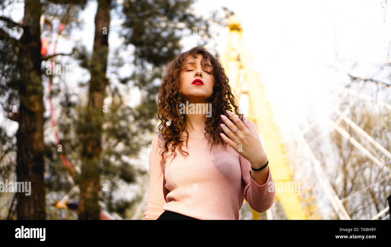 Women with long curly hair in the background of the Ferris wheel in ...