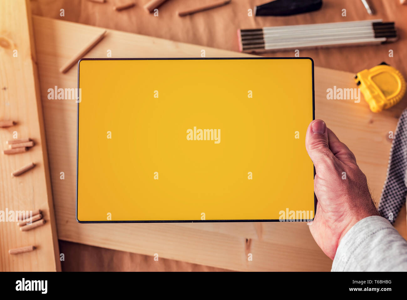 Carpenter holding digital tablet computer with blank mock up screen as ...