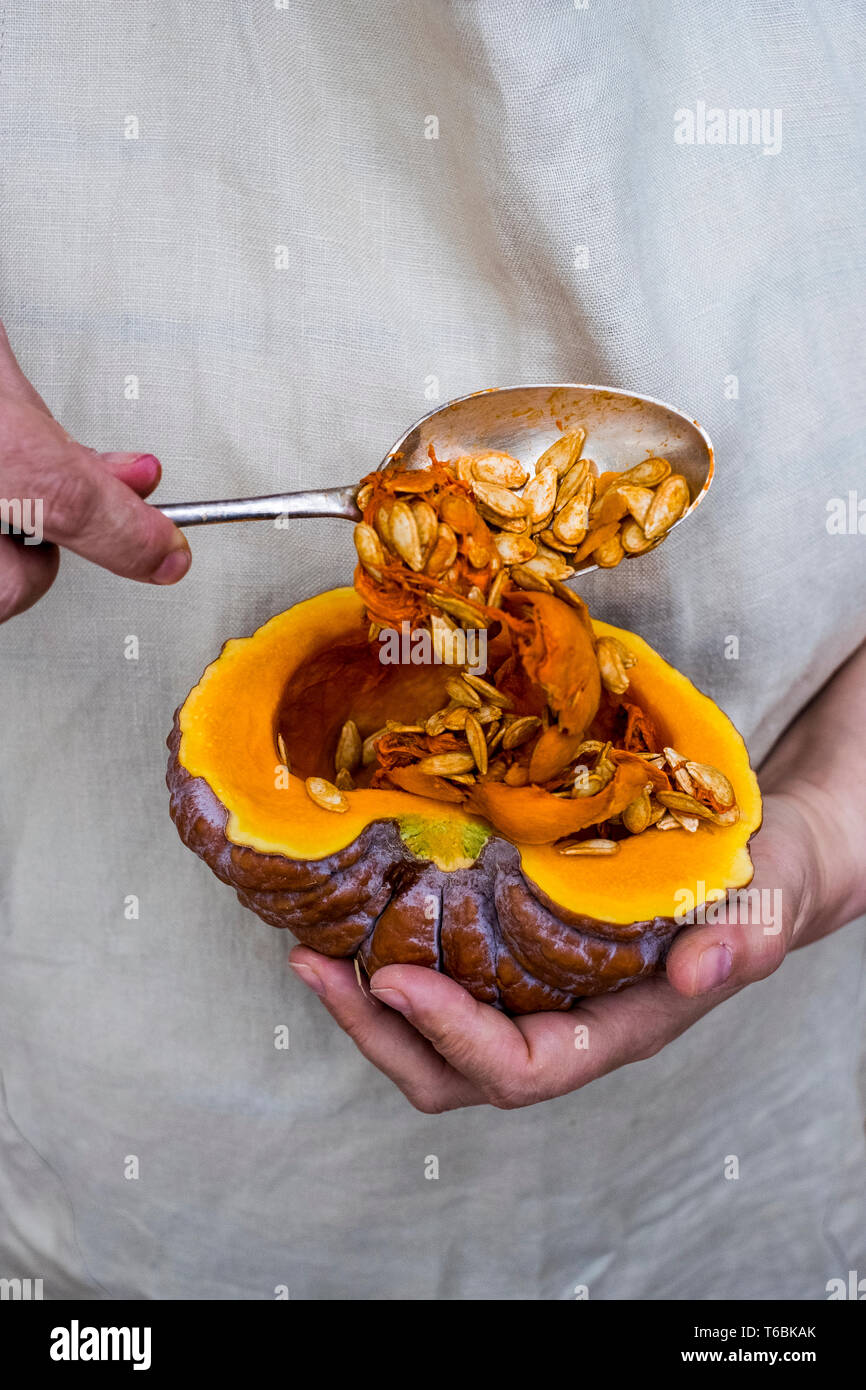 Close up of person using silver tablespoon to remove seed from a ...