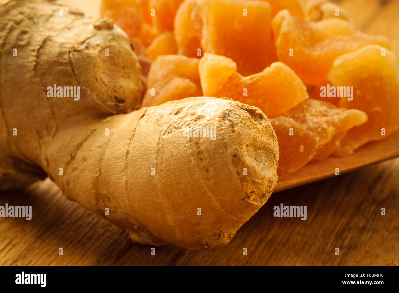 Closeup dried candied crystallized ginger pieces and fresh root on ...