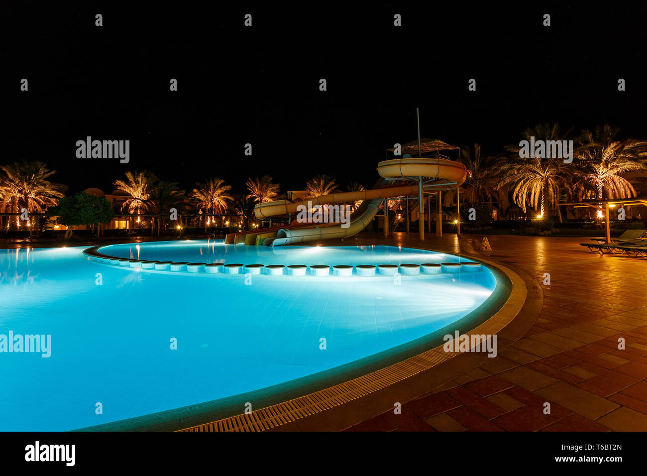 illuminated pool at night with tropical palms Stock Photo - Alamy