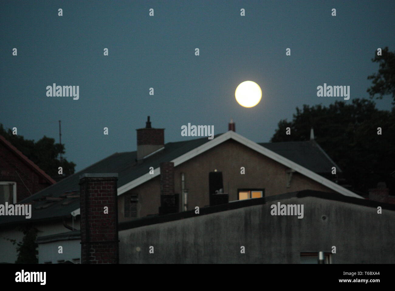 Full moon over roofs Stock Photo - Alamy