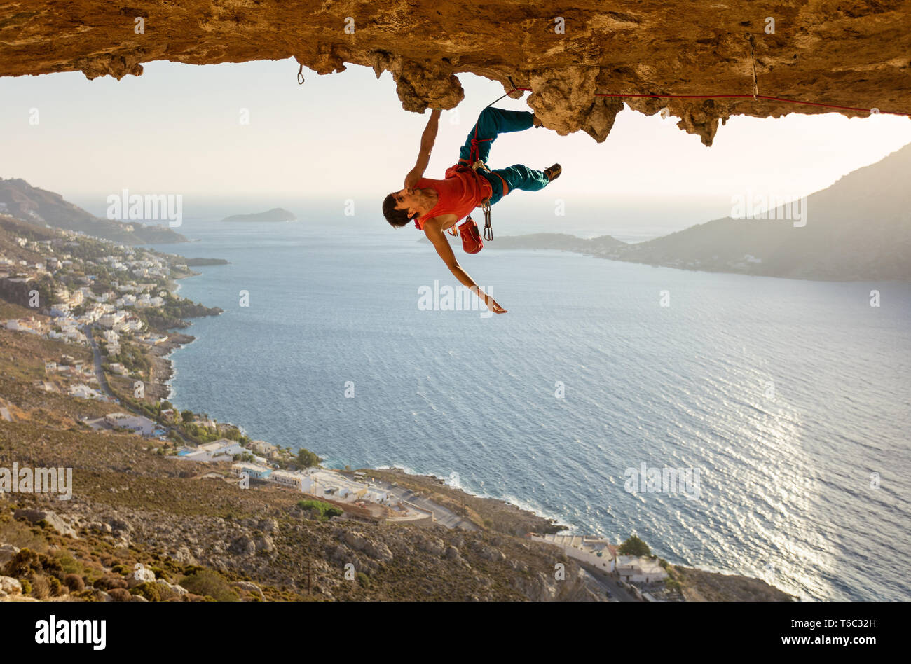 Caucasian male rock climber on challenging route going along ceiling in ...