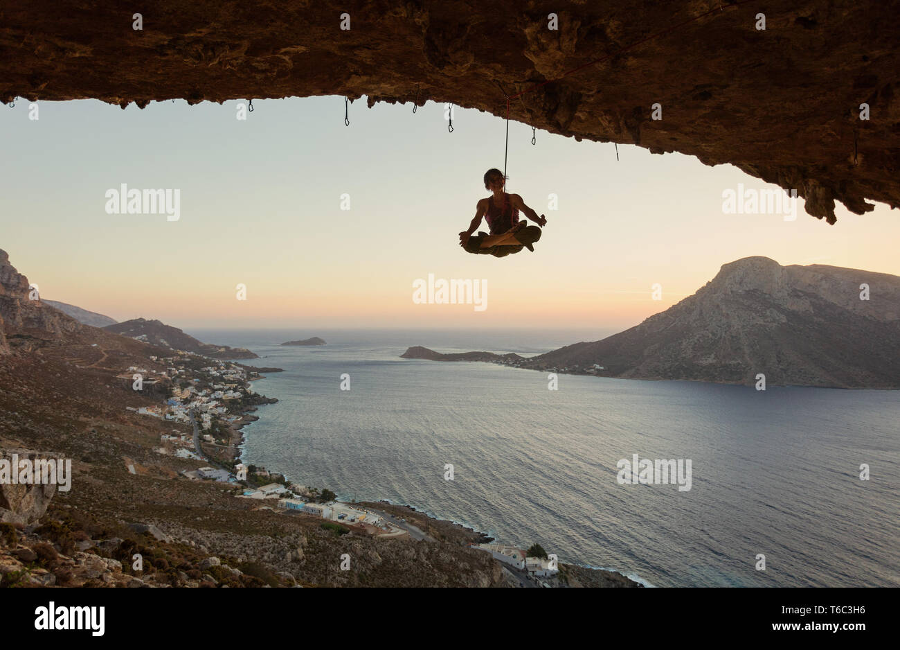 Young female rock climber hanging on rope in asana position. Rock ...