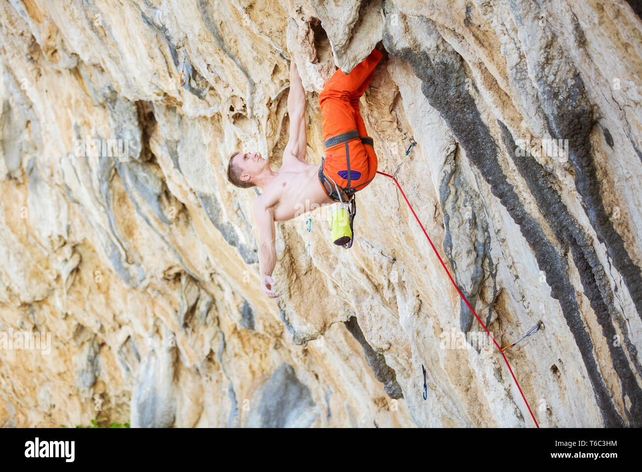 Caucasian young man climbing challenging route on overhanging cliff ...