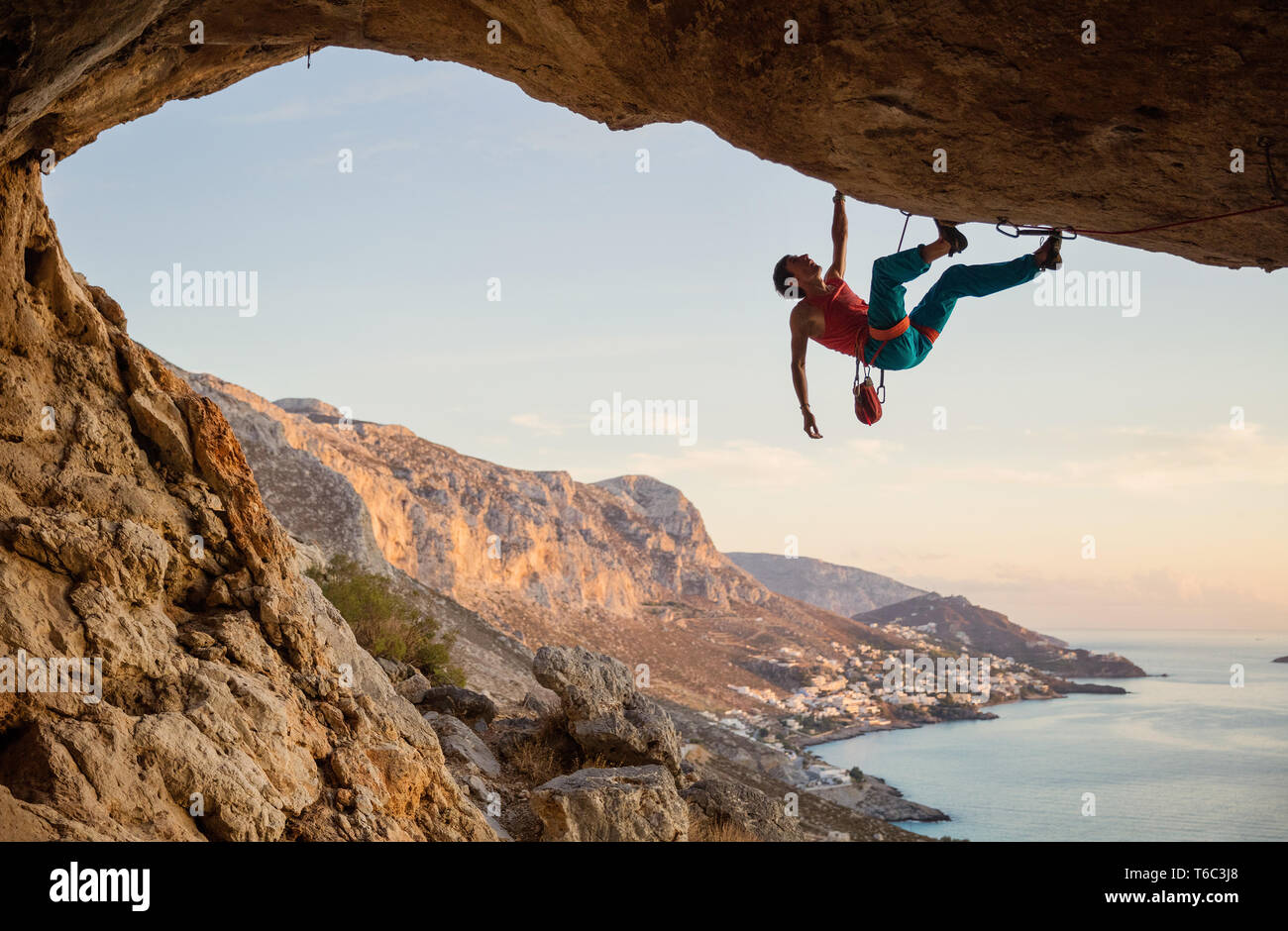 Caucasian man climbing challenging route going along ceiling in cave at ...