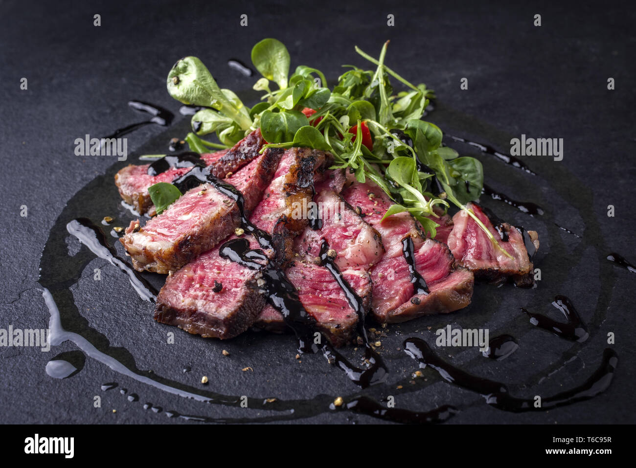 Barbecue aged Wagyu Tagliata di Manzo with lambs lettuce as close-up on ...