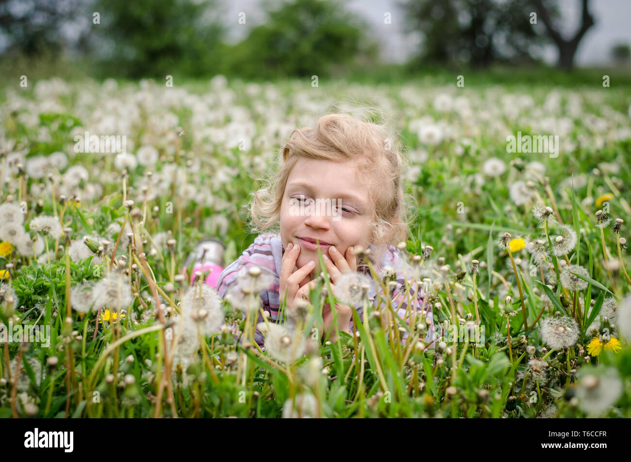 adorable smiling blond girl having fun in spring dandelion field Stock ...