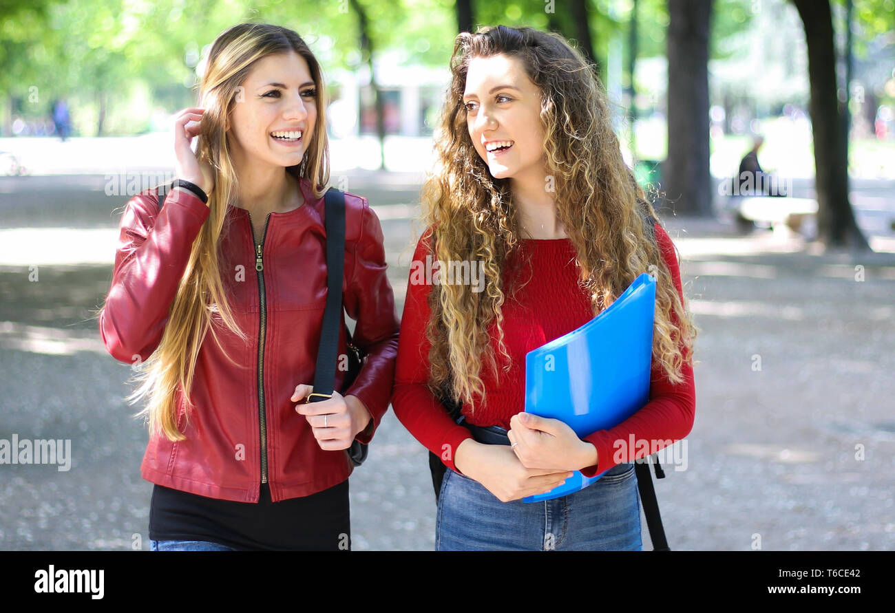 Two female schoolmates talking in a college courtyard Stock Photo - Alamy