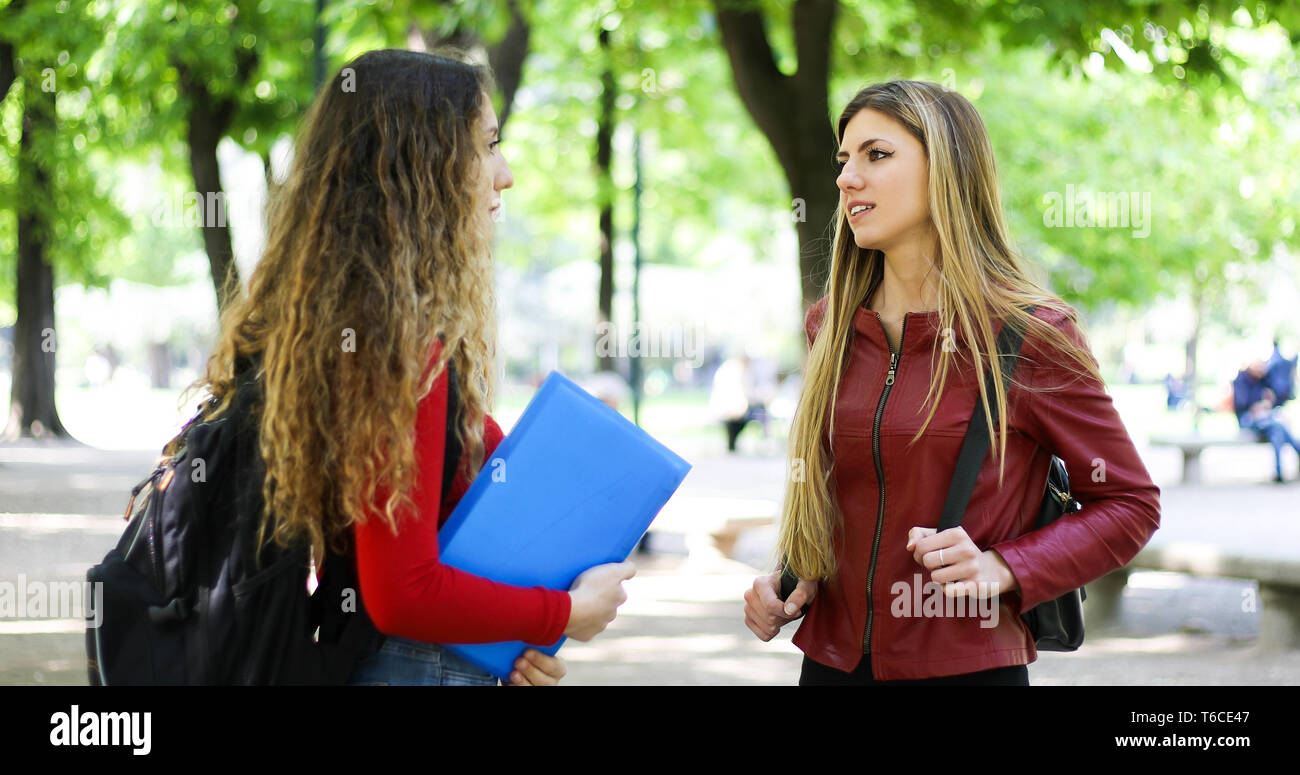 Two female schoolmates talking in a college courtyard Stock Photo - Alamy
