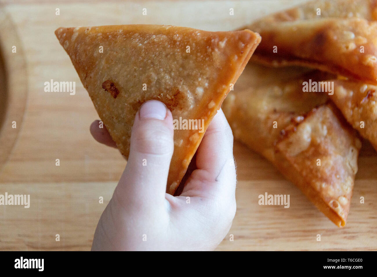 a close up view of a child holding a samosa in their hand ready to eat ...