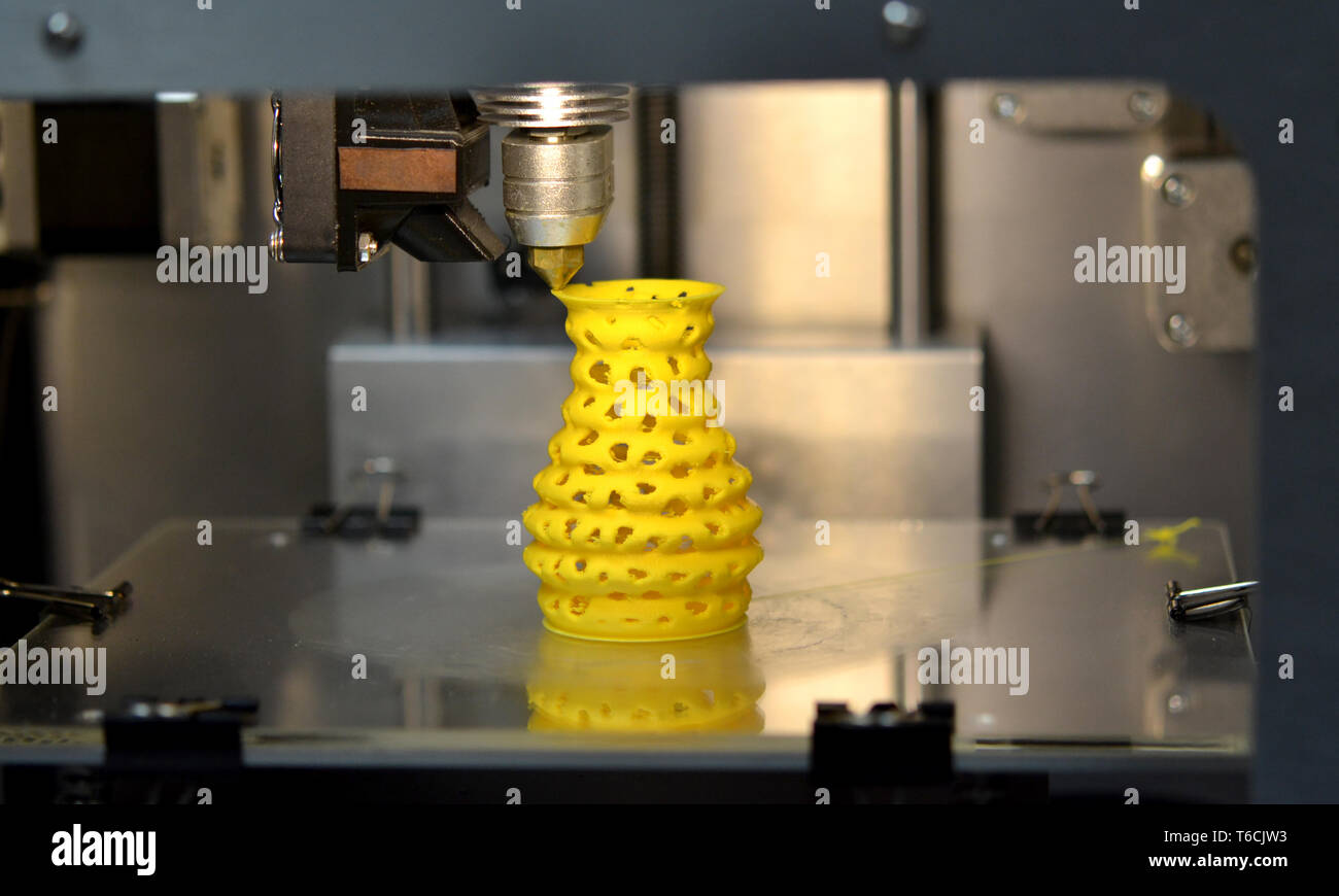 3D printer prints from the plastic figure closeup. 3D printer makes ...