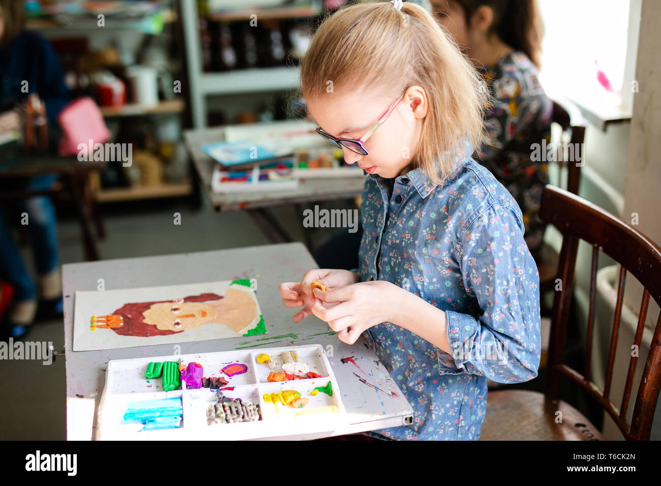 Smiling pretty blonde girl enjoying their time at art studio. close up ...