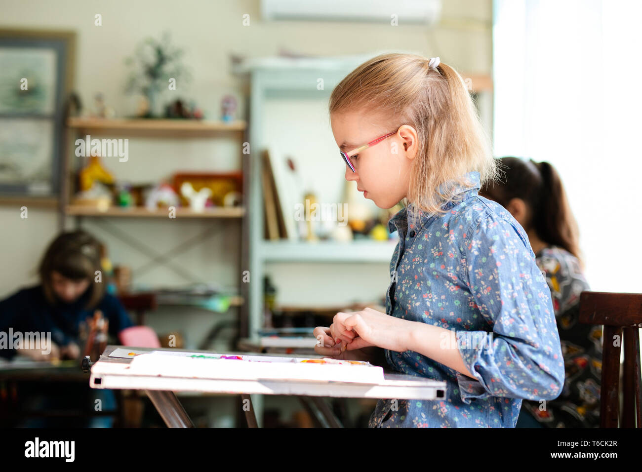 Smiling pretty blonde girl enjoying their time at art studio. close up ...