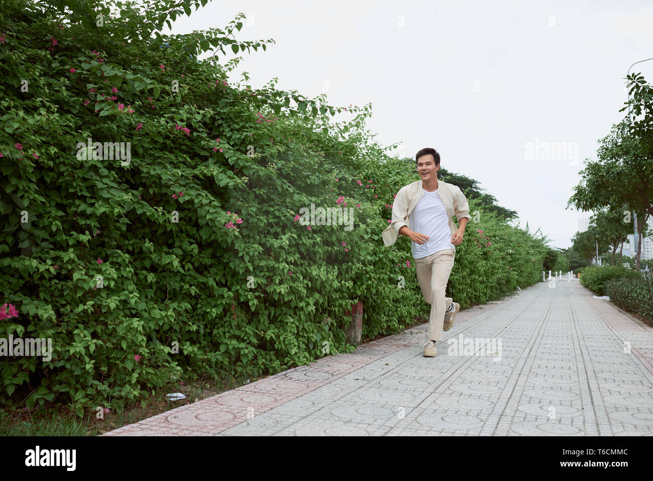 Smiling young man running in the park during summer Stock Photo - Alamy