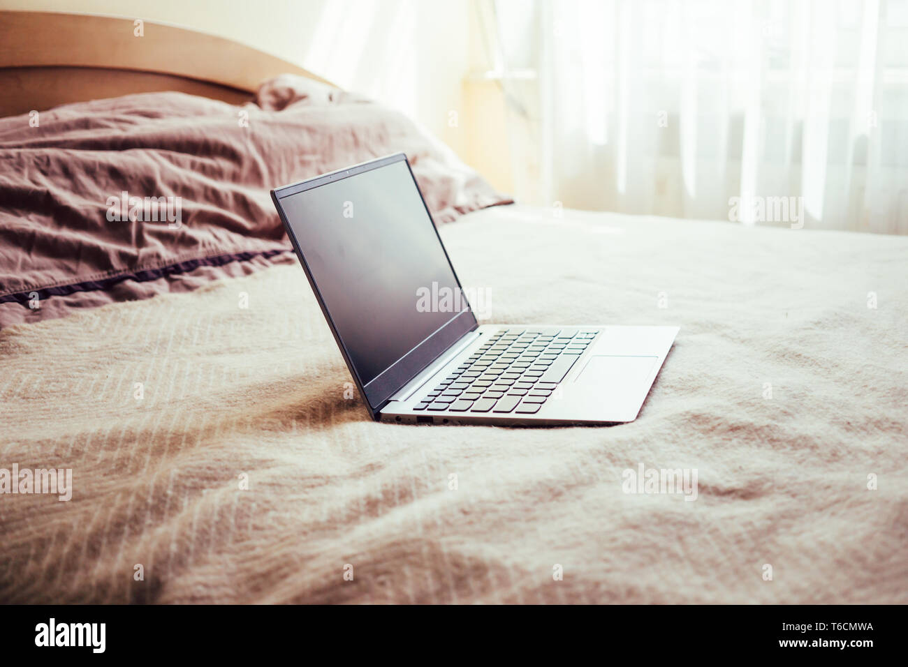 New laptop with blank screen on bed blanket in cozy home bedroom ...