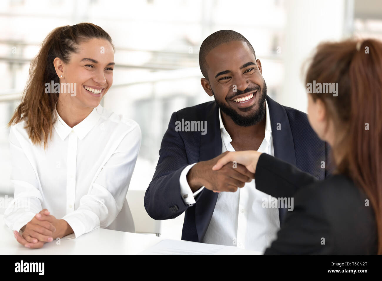 Happy mixed ethnicity couple clients handshake insurer realtor making ...
