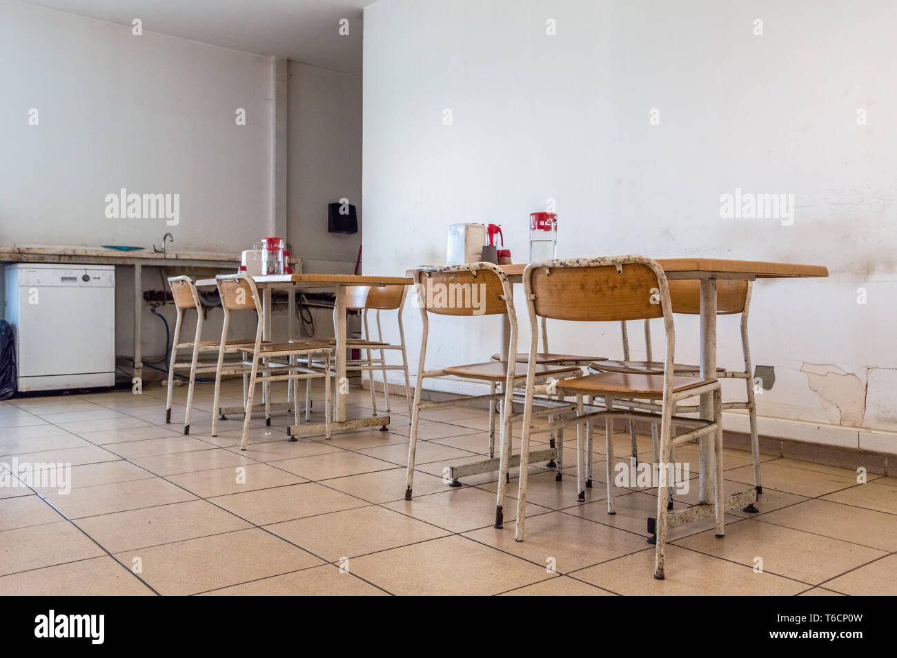 Empty dining hall of a factory with old chairs and water-bottles on ...