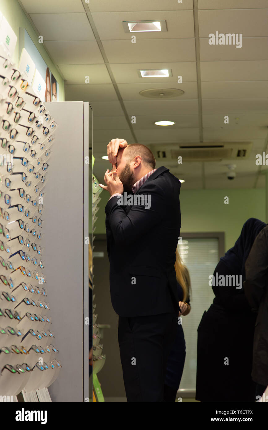 Interior of a optician store with costumers looking for spectacles ...