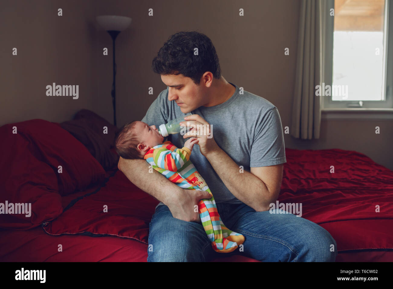 Young Caucasian father feeding newborn baby son daughter with milk ...