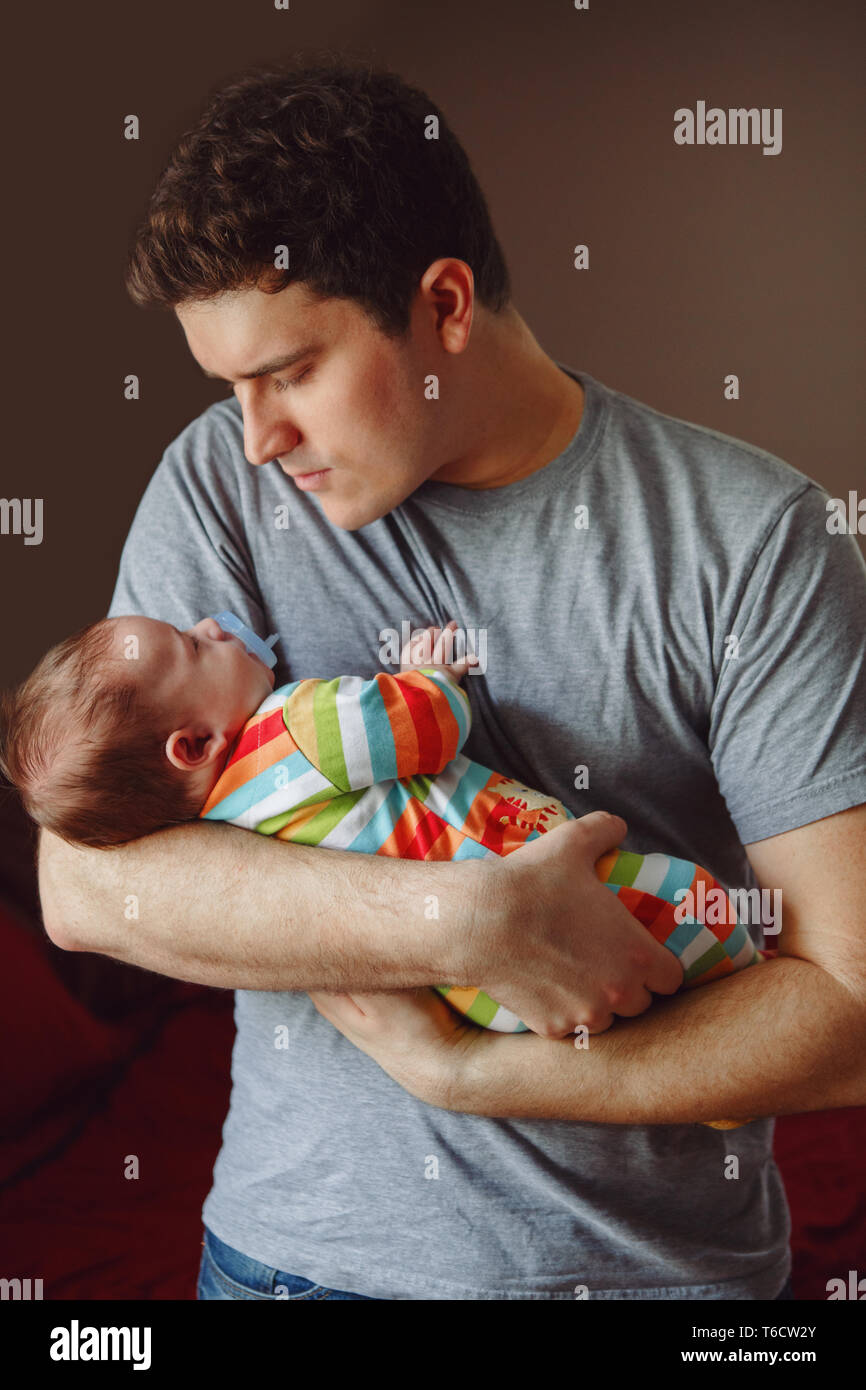 Young Caucasian father trying to calm down newborn baby. Male man ...