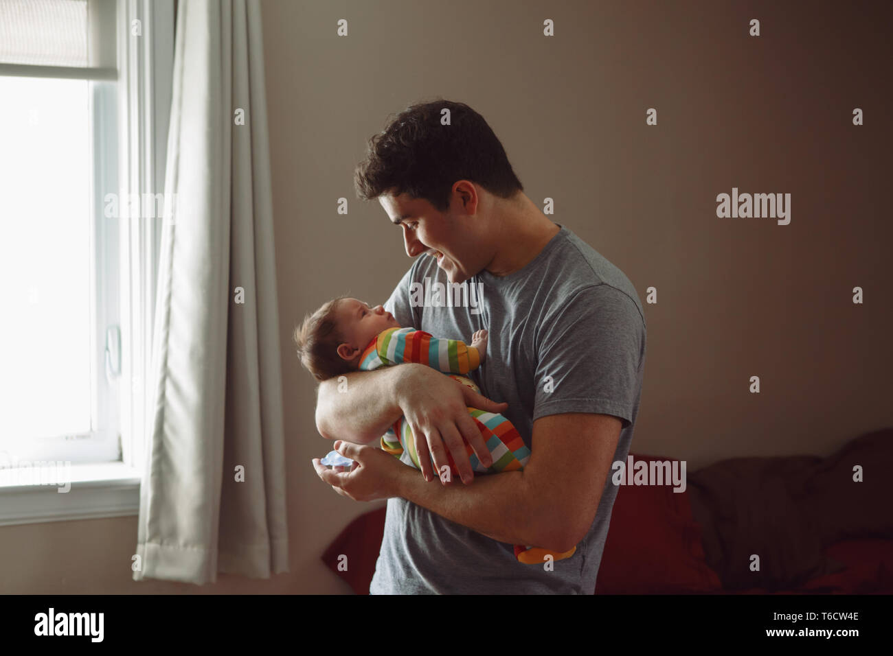 Young Caucasian father trying to calm down newborn baby. Happy smiling ...