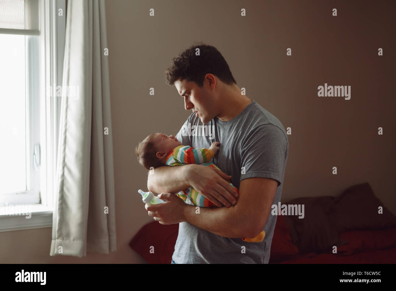 Young Caucasian father feeding newborn baby son daughter with milk ...
