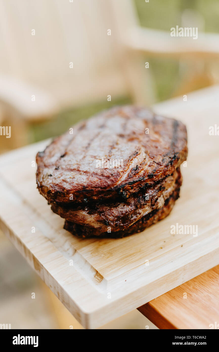 well done dry-aged Rib Eye Steak on a cutting board outside in the ...