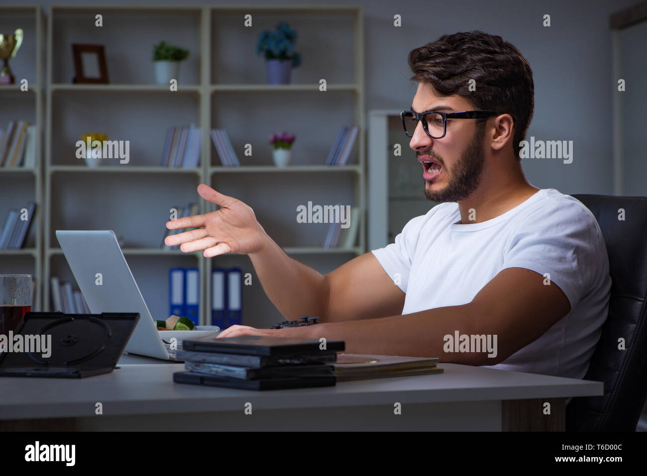 Young man staying late in office to do overtime work Stock Photo - Alamy
