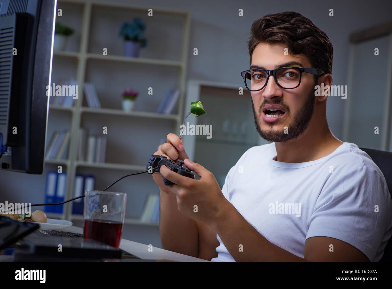 Young man playing games long hours late in the office Stock Photo - Alamy