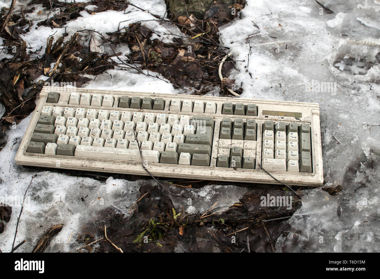 Abandoned dirty broken grunge computer keyboard on snowy frozen soil ...