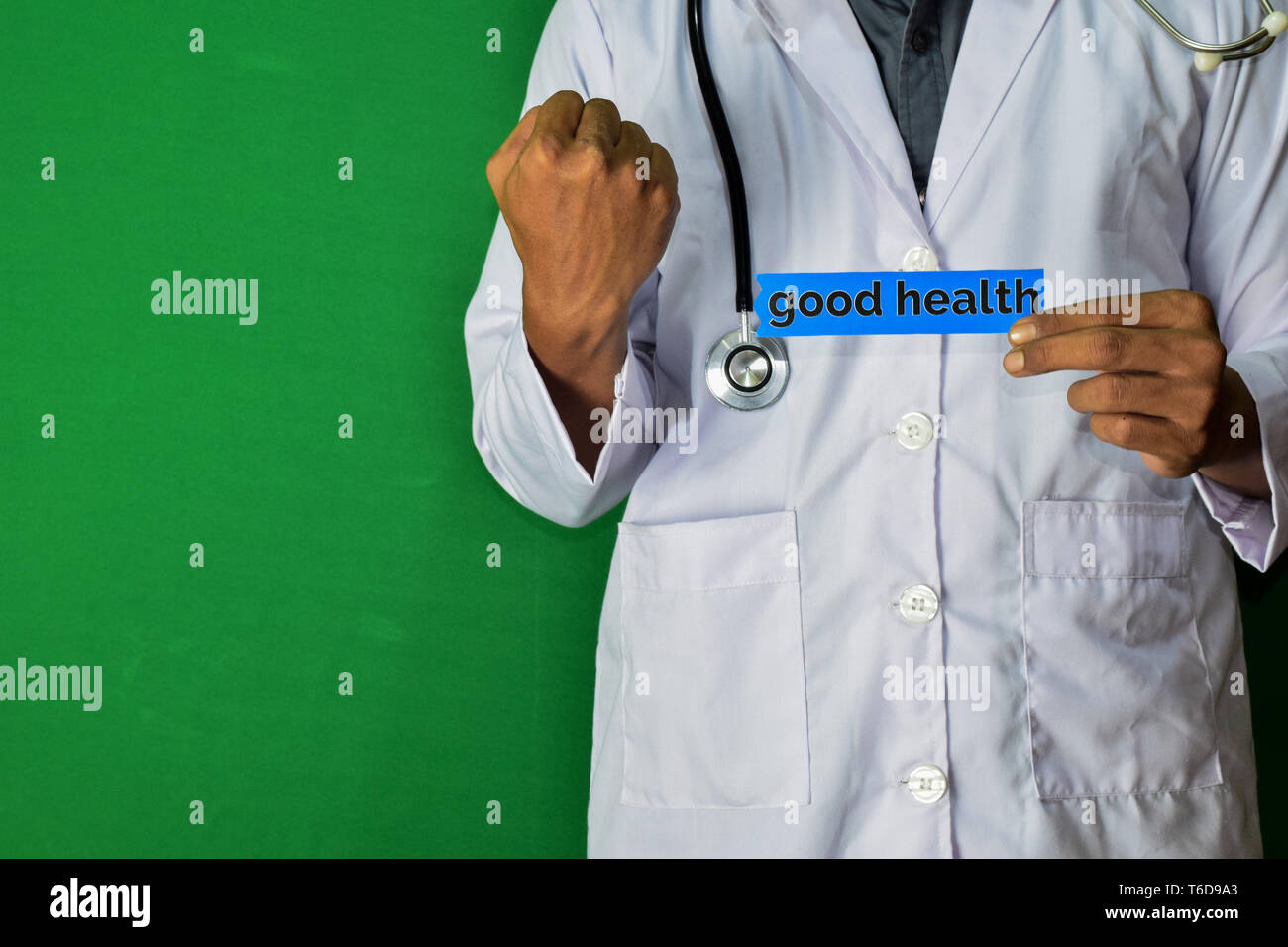 A doctor standing, Hold the Good Health paper text on Green background ...