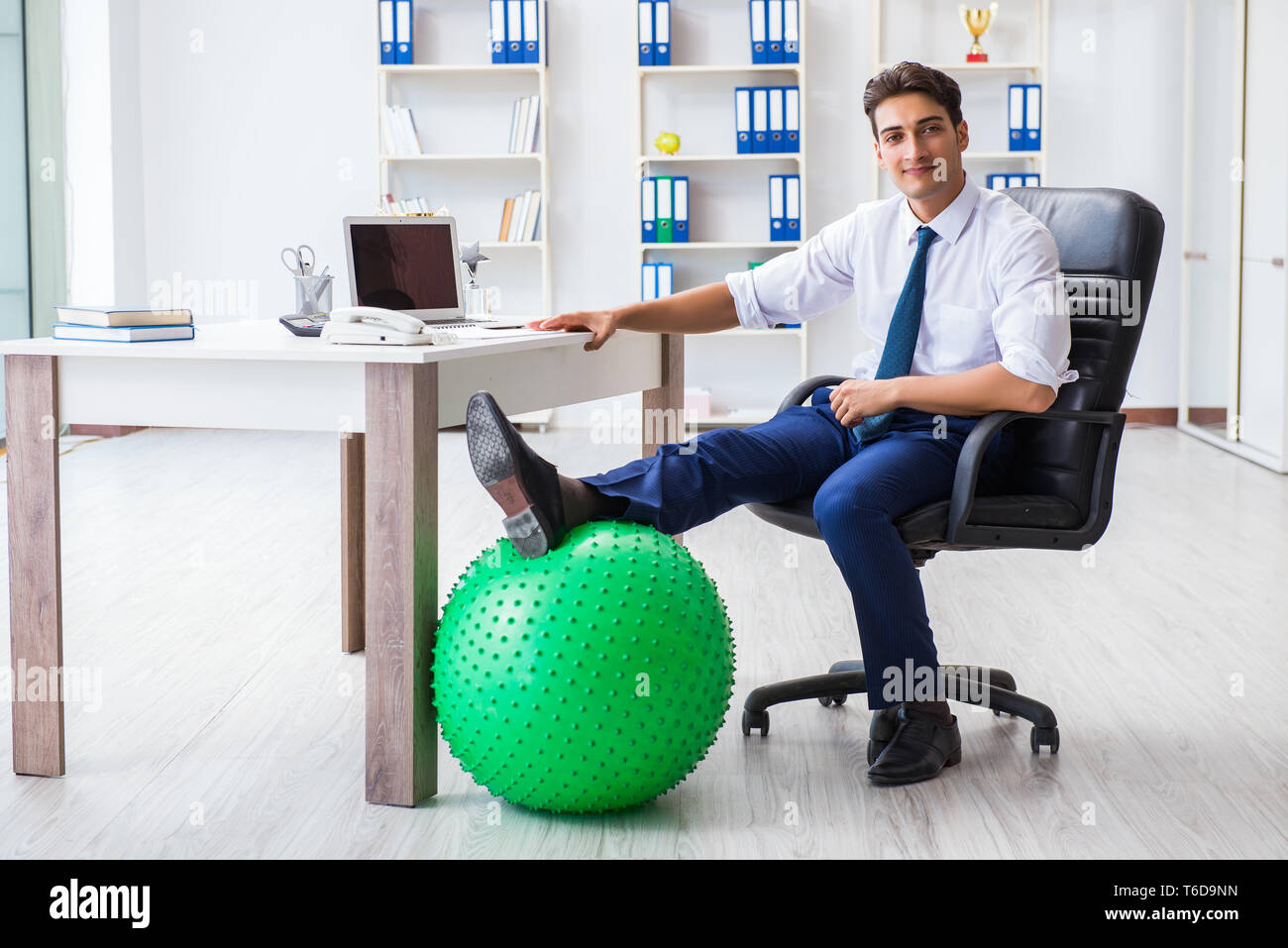 Young businessman doing sports stretching at workplace Stock Photo - Alamy