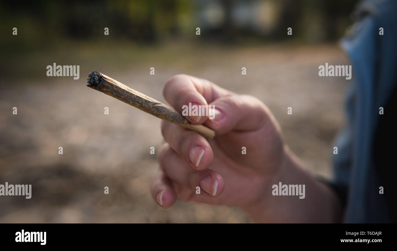 The person smoking marijuana joint outdoors. Cannabis joint in the hand ...
