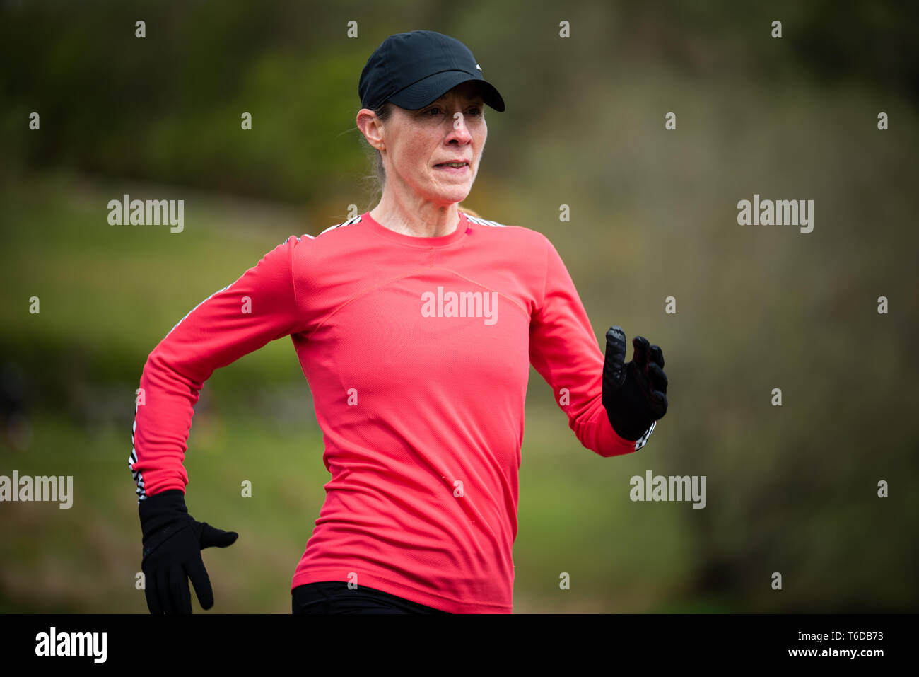 Fit senior woman in 50s exercising and keeping fit by running in a park ...