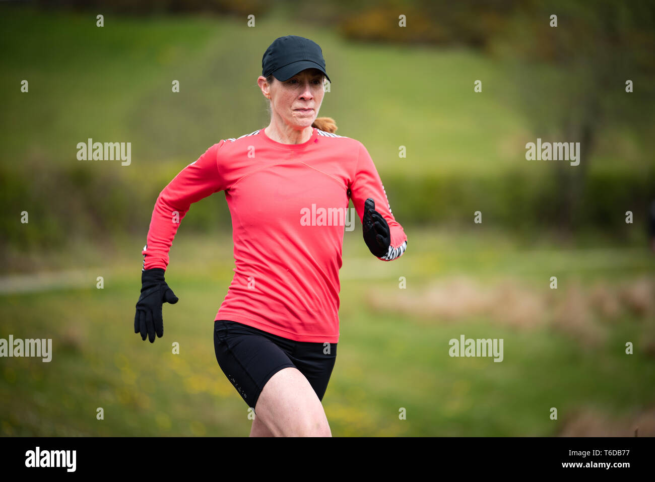 Fit senior woman in 50s exercising and keeping fit by running in a park ...