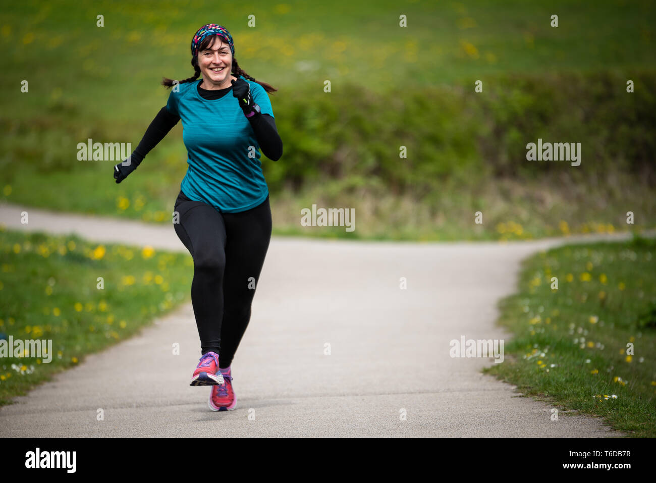 Senior woman in 50s exercising and keeping fit by running in a park ...