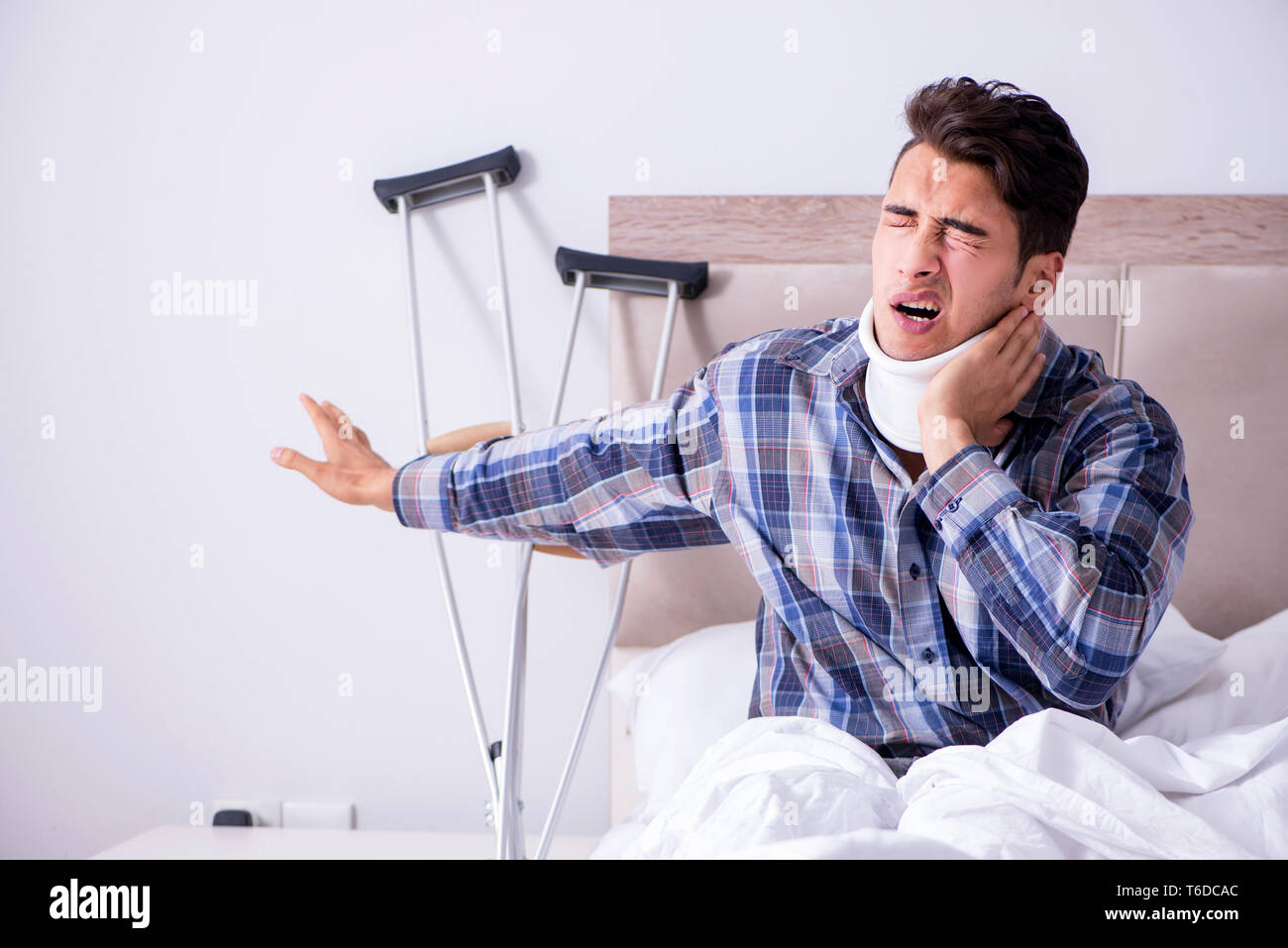 Injured man in bed at home with crutches Stock Photo - Alamy