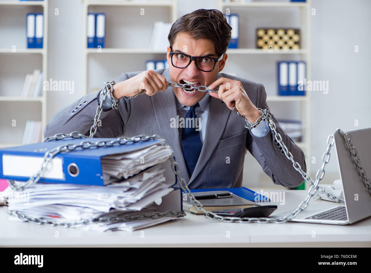 Busy employee chained to his office desk Stock Photo - Alamy